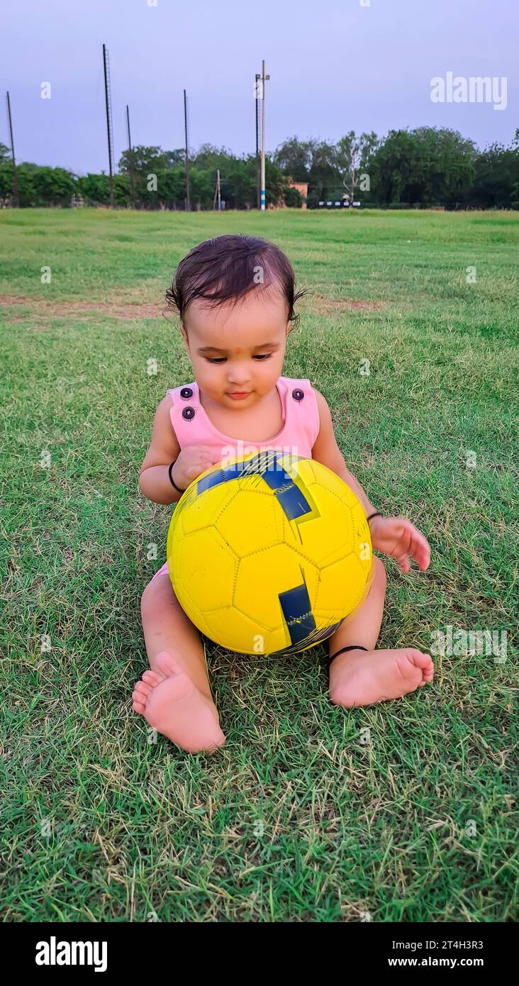 cute infant playing with football at green grass field from different ...