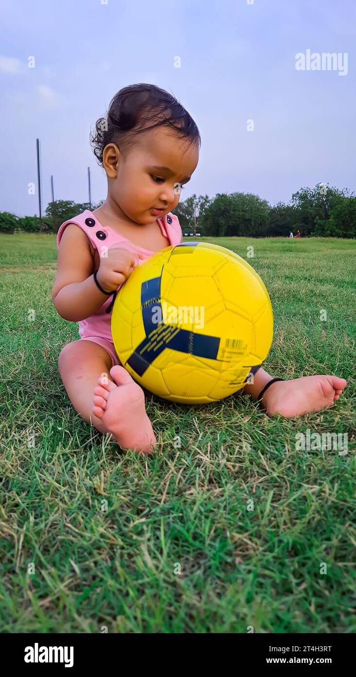 cute infant playing with football at green grass field from different ...