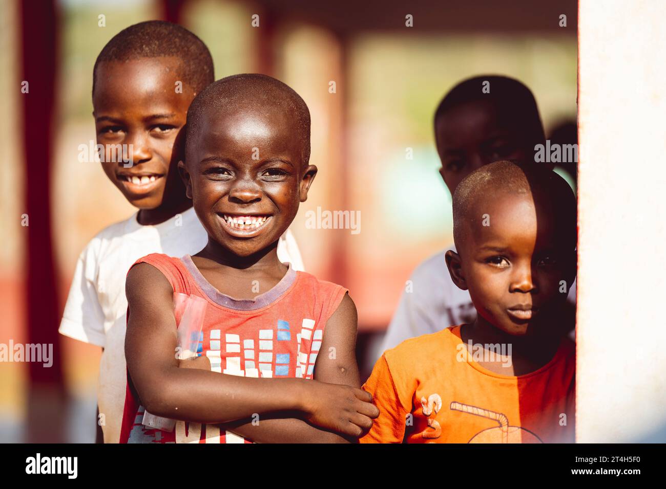 The three happy children wearing red and orange clothes smiling at the ...