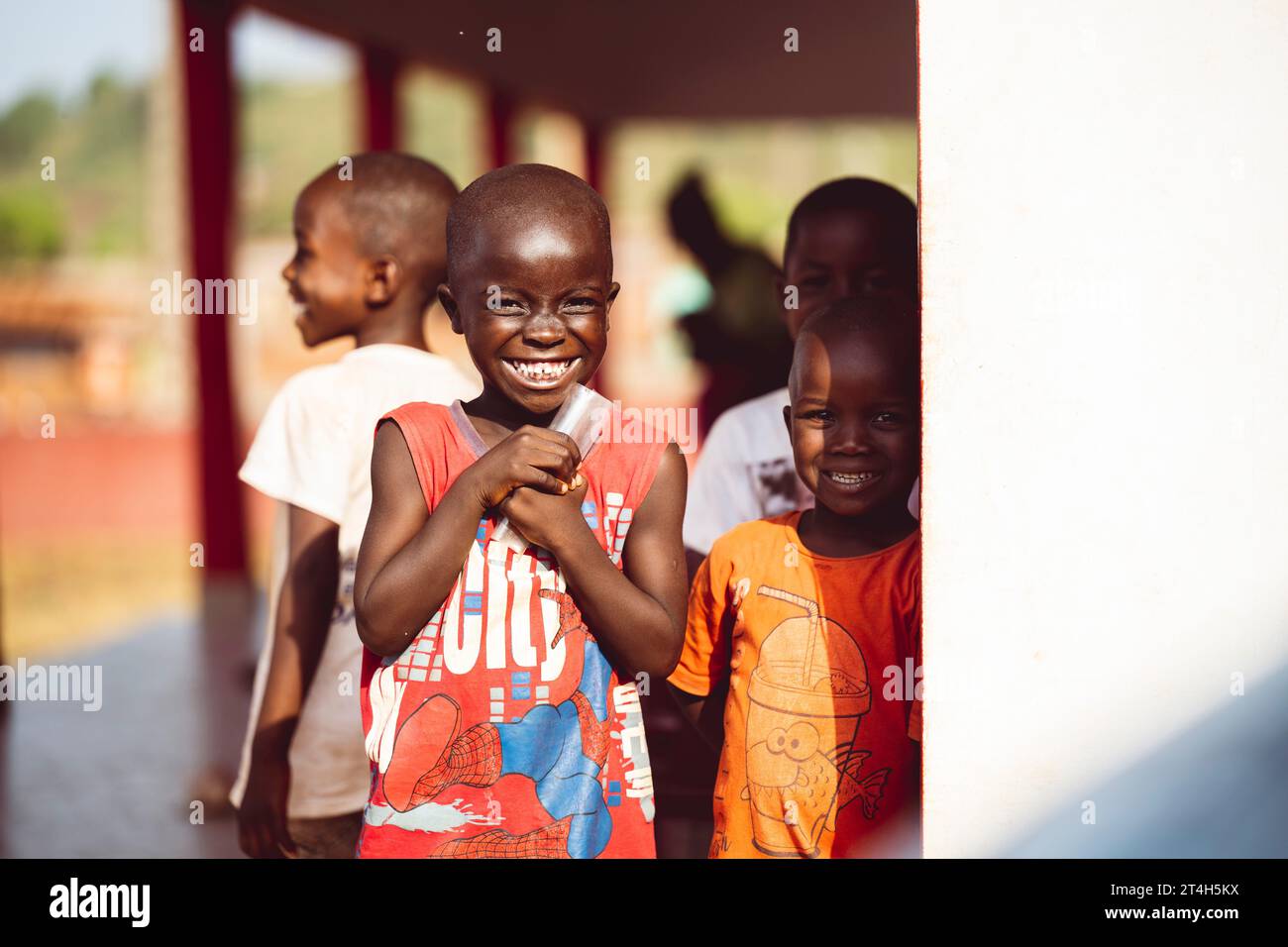 The three happy children wearing red and orange clothes smiling at the ...