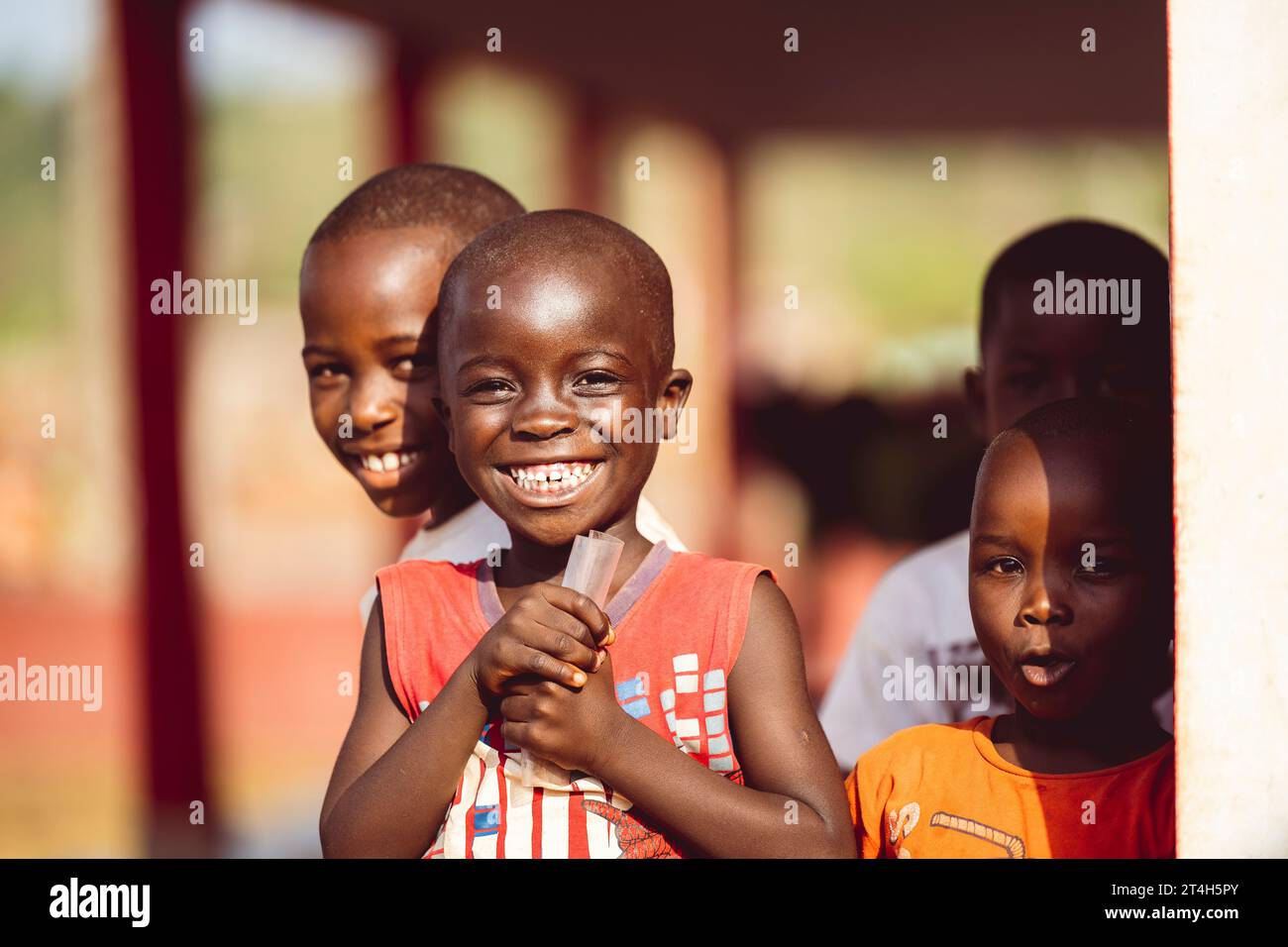 The three happy children wearing red and orange clothes smiling at the ...