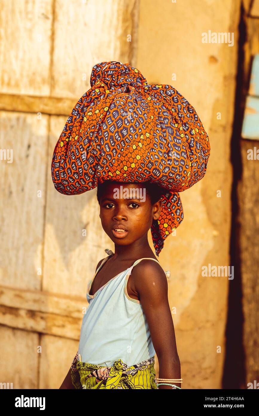 An African Girl Wearing Traditional Attire Holding A Large Bag On Her Head In Abidjan Cote D
