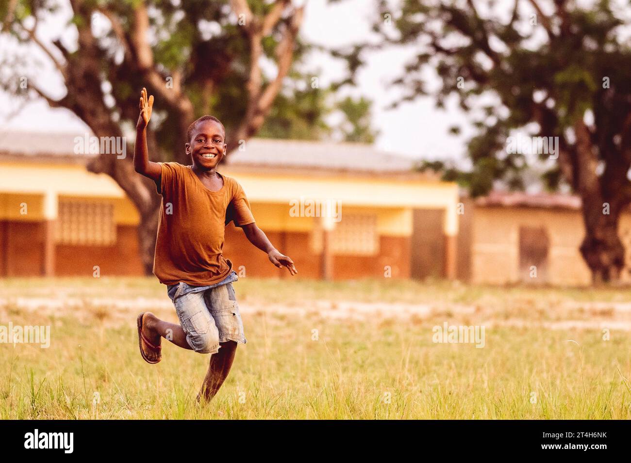 A spirited young boy sprinting across a grassy landscape in Abidjan ...