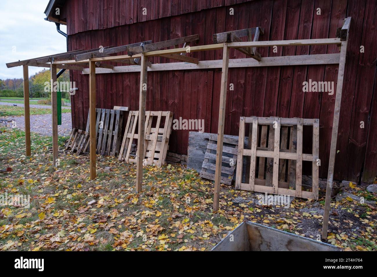 Building firewood storage against red barn wall Stock Photo - Alamy