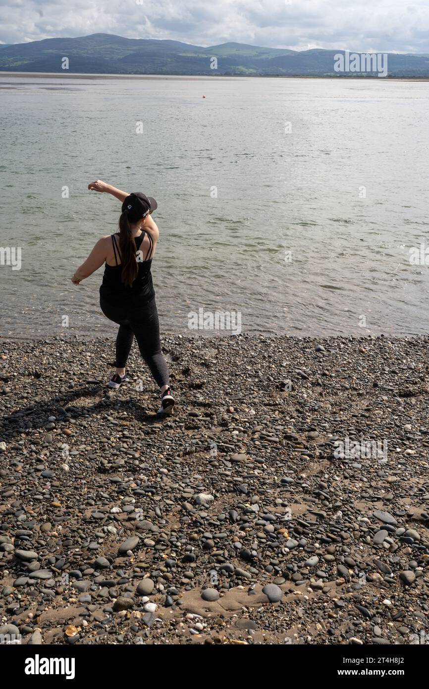 A young female skipping stones in the sea in Aberaeron Beach Stock Photo - Alamy