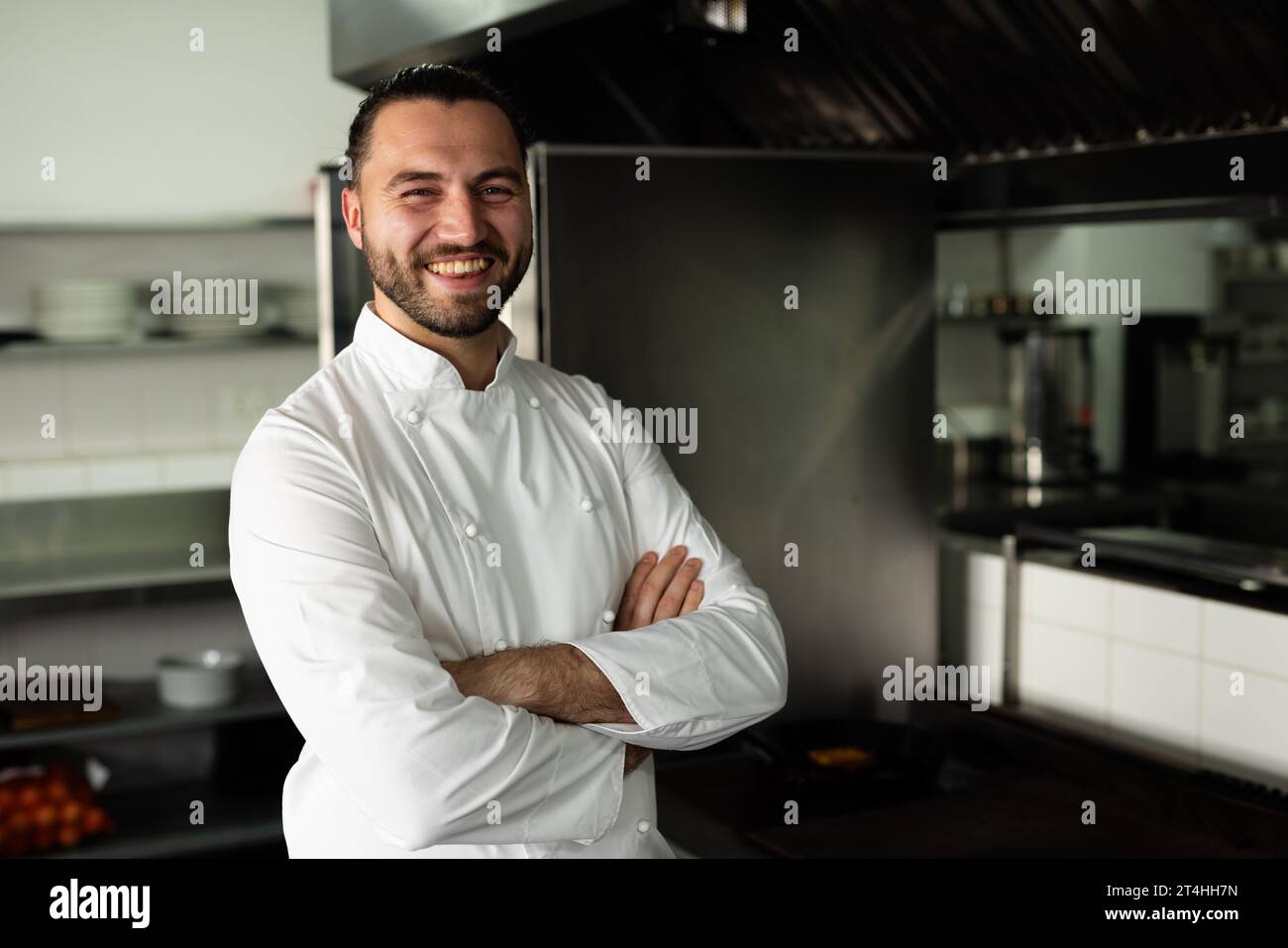 Portrait of smiling caucasian male chef with arms crossed standing in ...