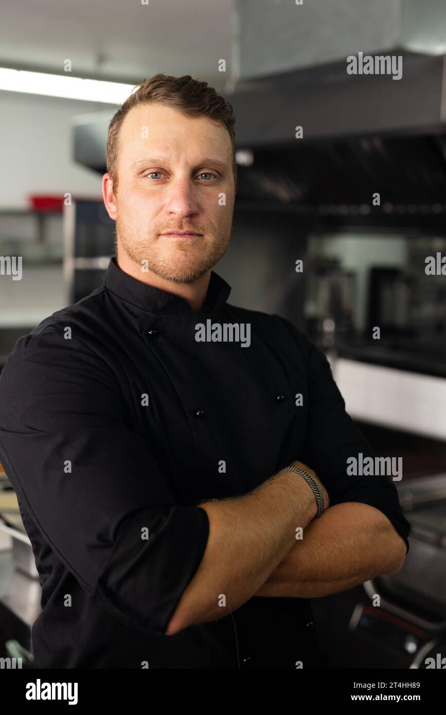Confident caucasian male head chef in black uniform with arms crossed ...