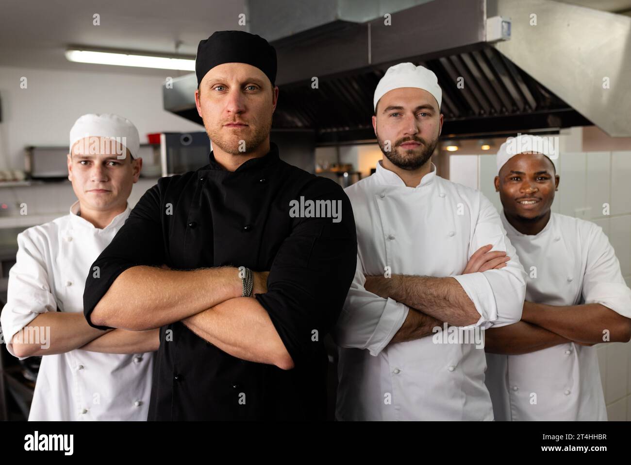 Portrait of diverse male head chef with students standing confidently ...