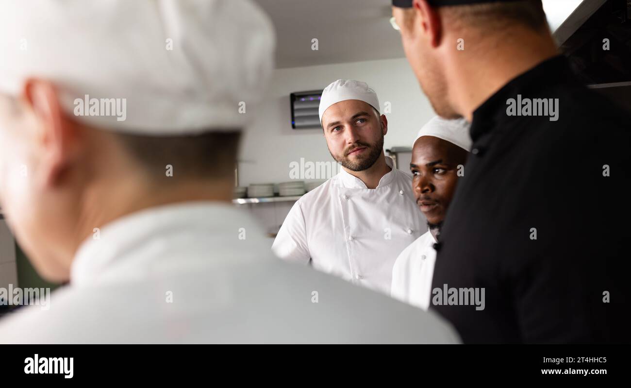 Diverse male students looking and listening to chef teacher in ...