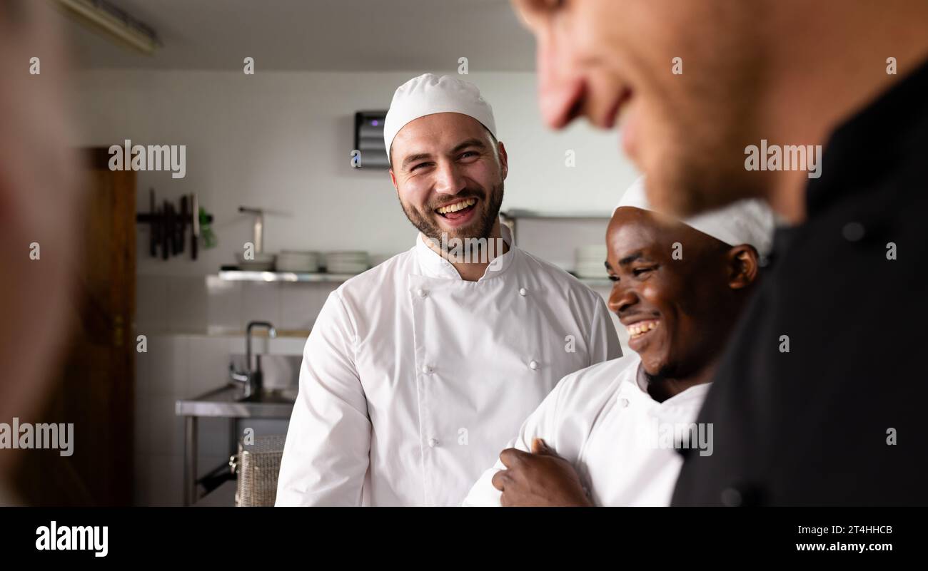 Diverse male students laughing and learning cooking from chef teacher ...