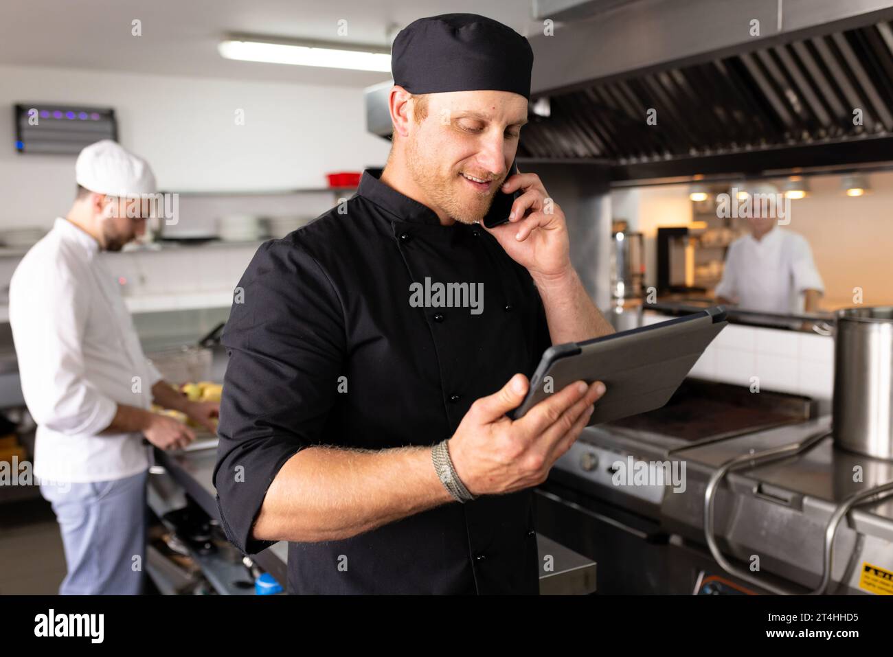 Caucasian male chef teacher using tablet and talking over cellphone ...