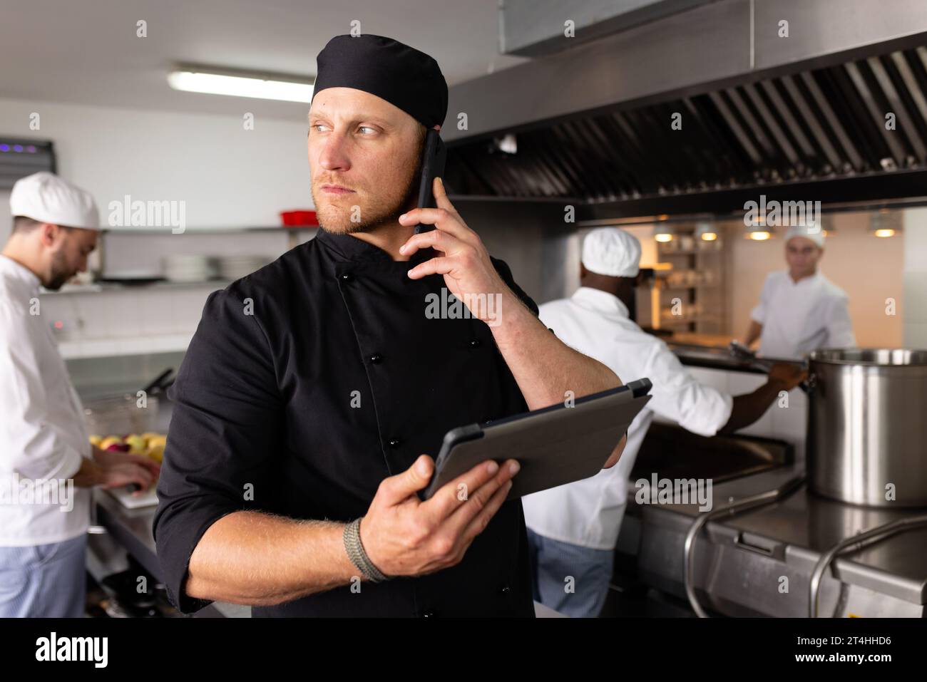 Diverse male chef teacher using tablet and talking over smartphone with ...