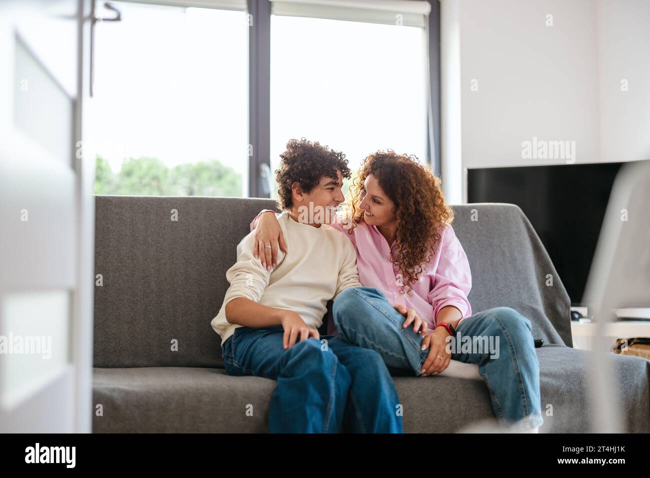Happy mother and son sitting on sofa in living room at home Stock Photo ...