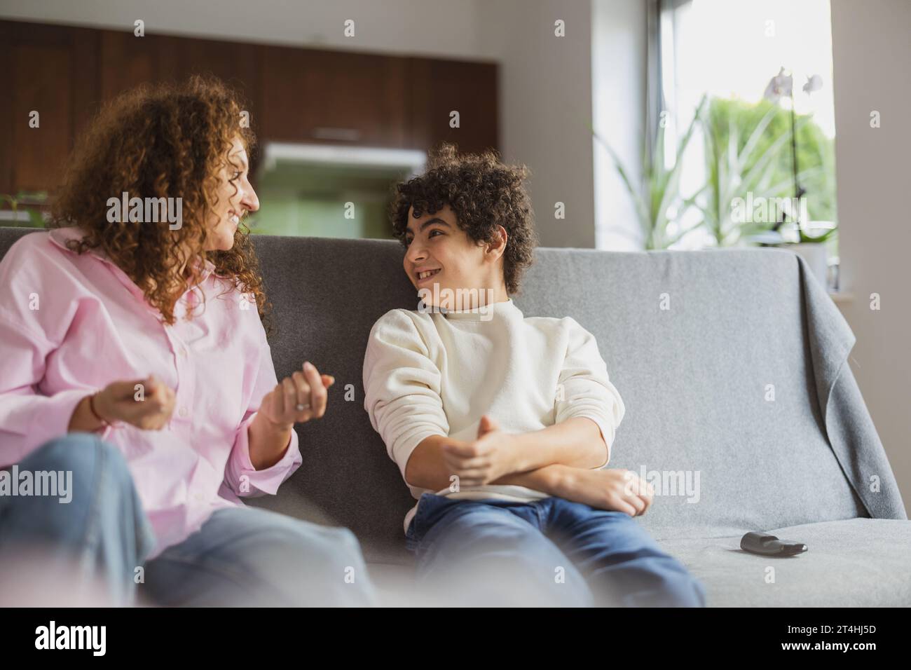 Happy mother and son sitting on sofa in living room at home Stock Photo ...