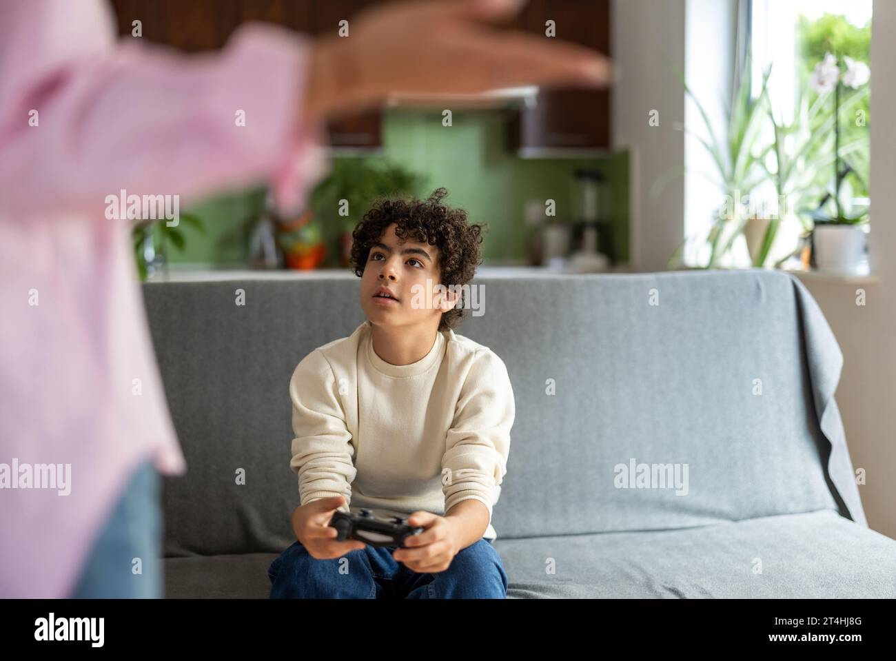 Teenage boy playing video games while his mother is not happy about it ...