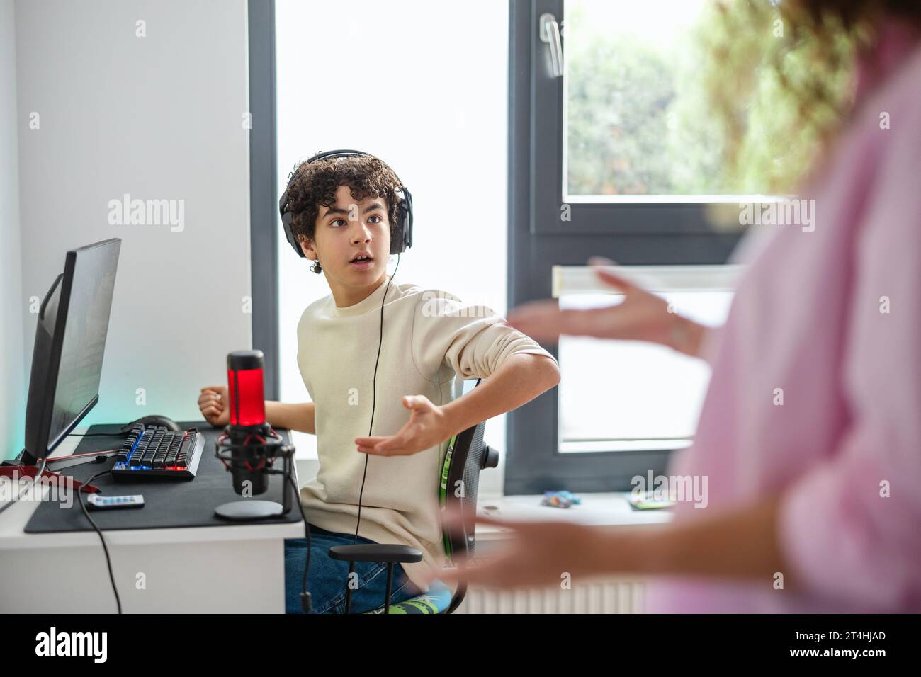 Teenage boy playing video games while his mother is not happy about it ...