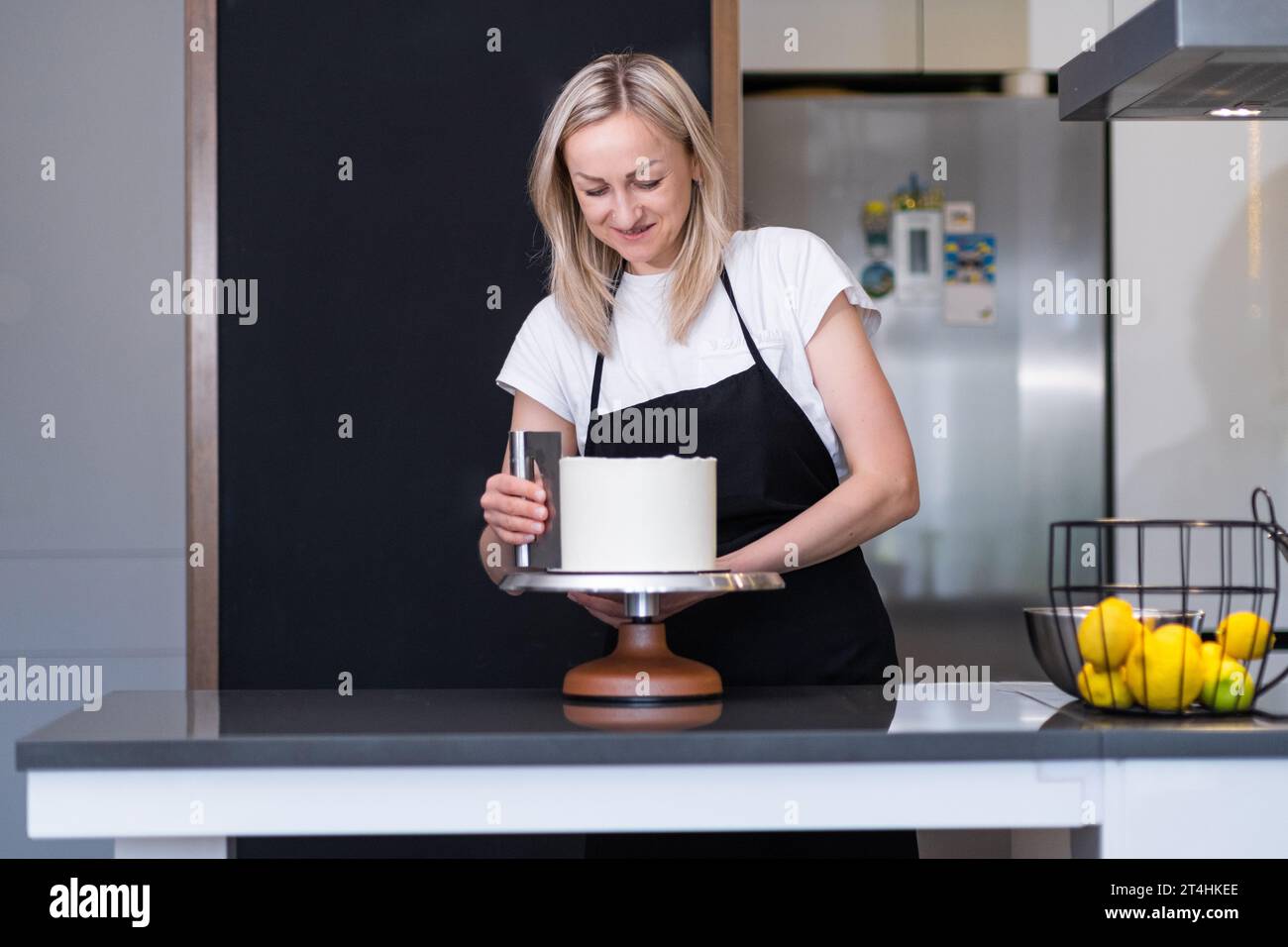 Happy blonde woman finishing processing white mastic on sugar free cake ...