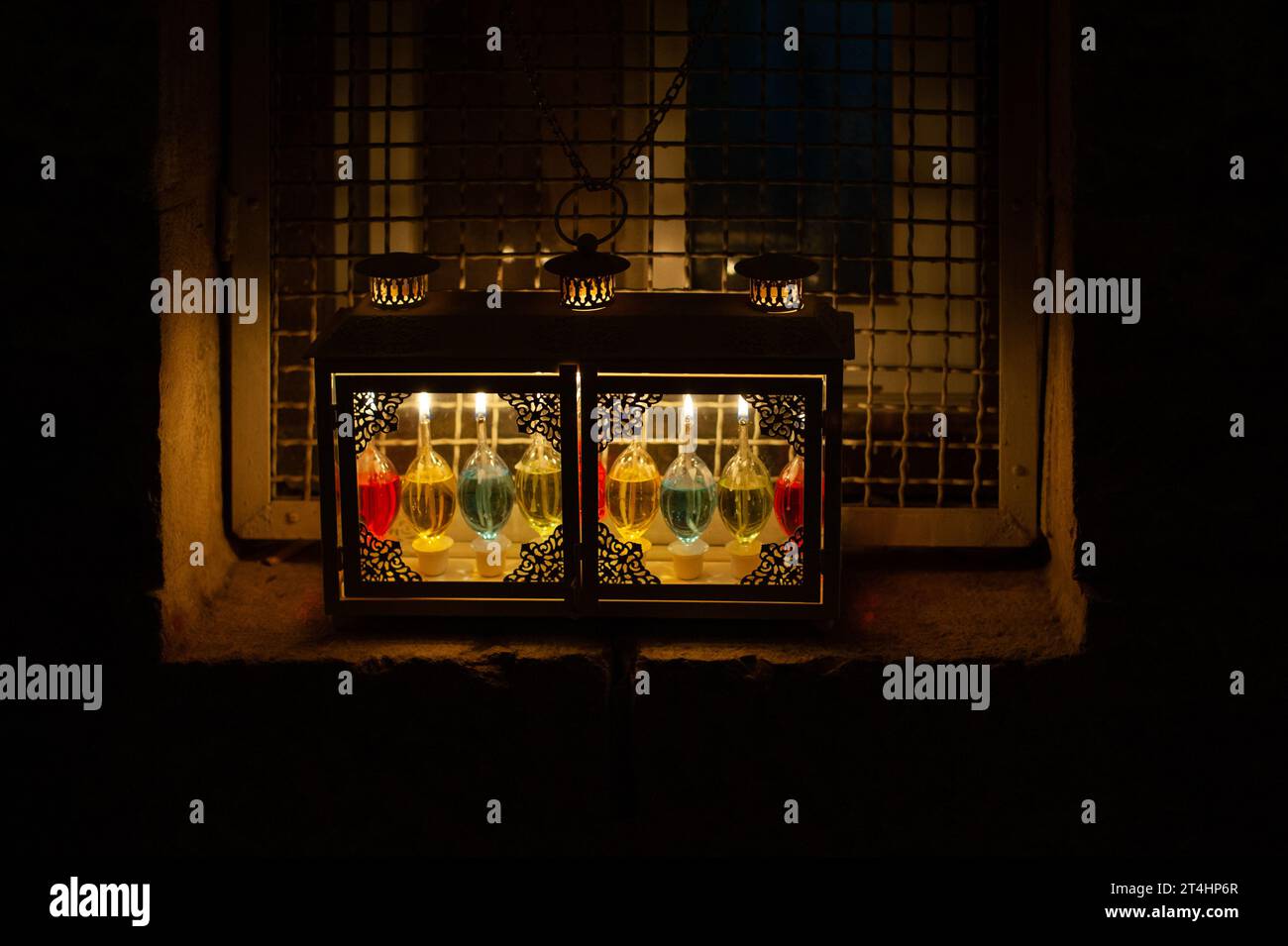 A Hanukkah menorah using glass vials and colorful parafin candles burns ...