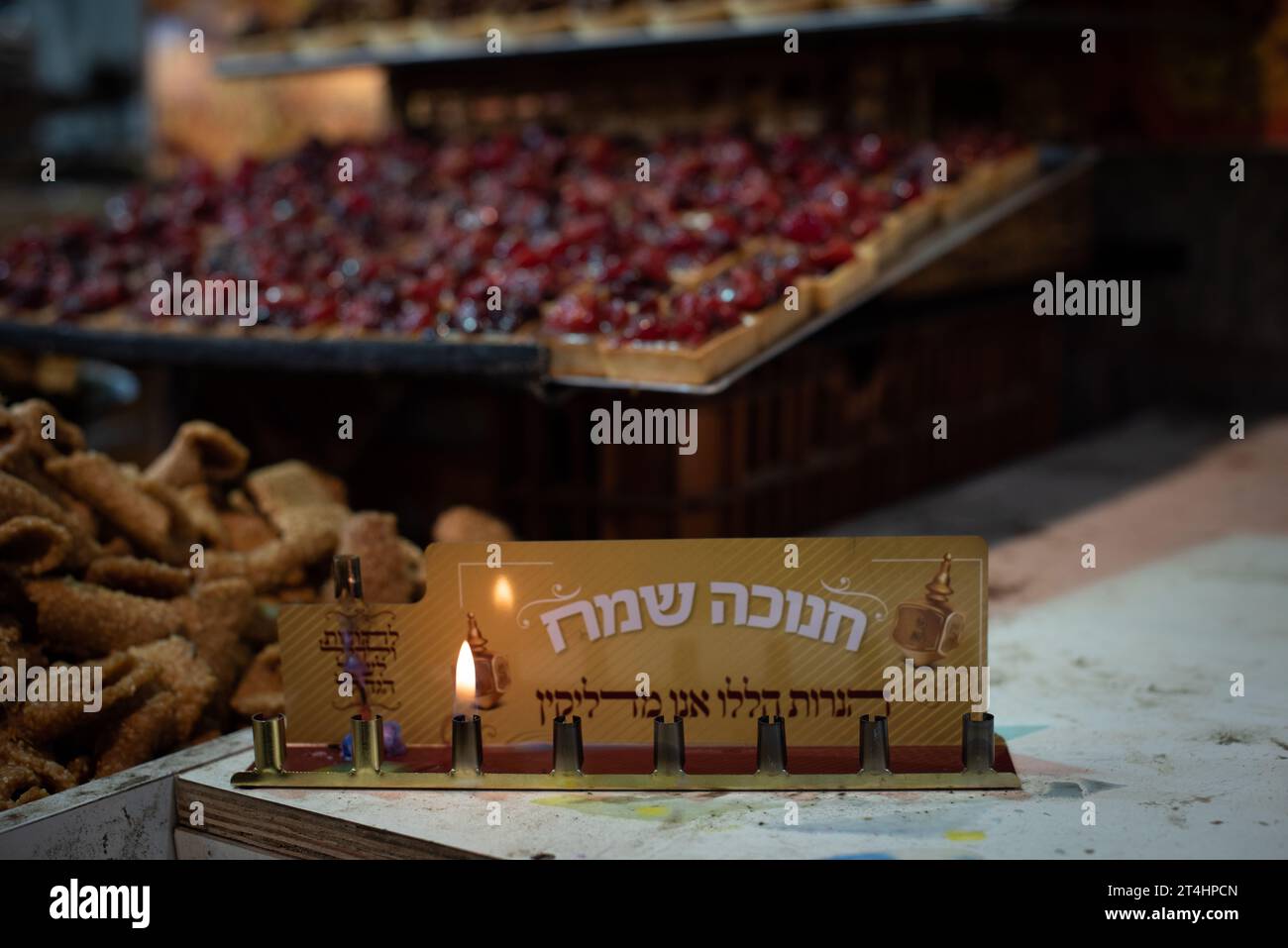 A single, small flame remains lit in a Hanukkah menorah inscribed with ...