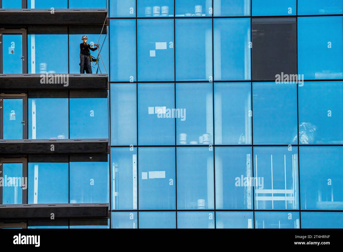 A construction worker checks his safety gear while working on a balcony ...