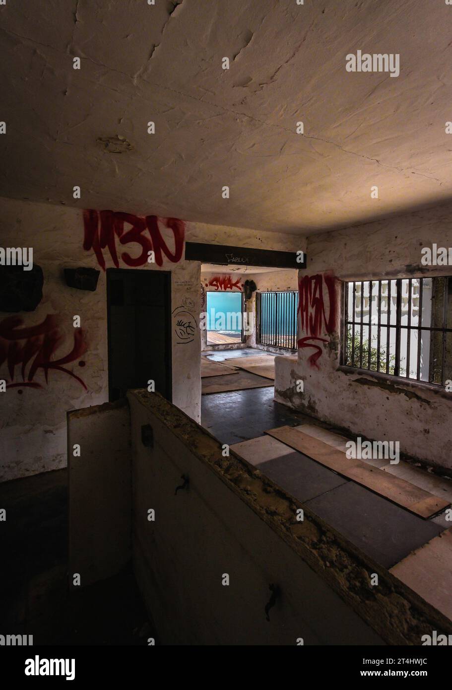 An abandoned industrial building with multiple windows broken, featuring graffiti art on the ...