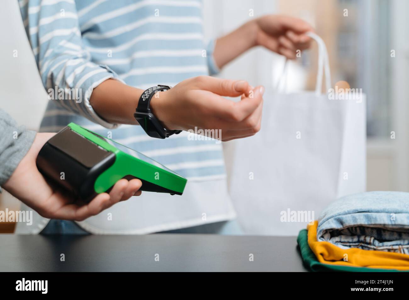 Modern woman using terminal for contactless payment with smartwatch on ...