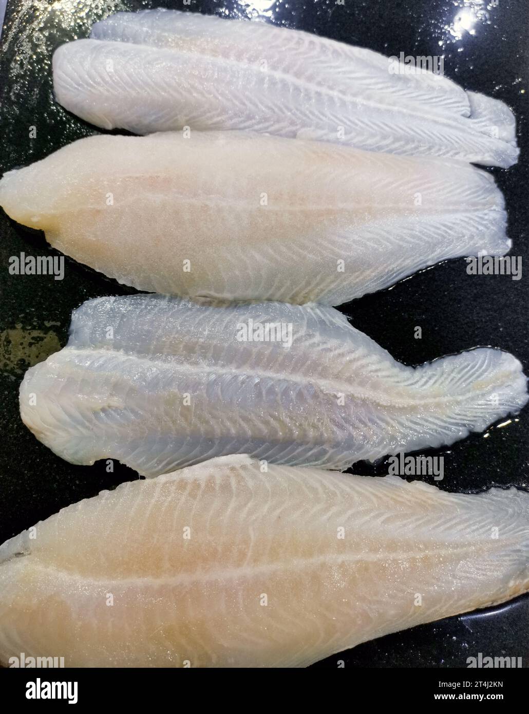White fish fillet on a black tray Stock Photo - Alamy