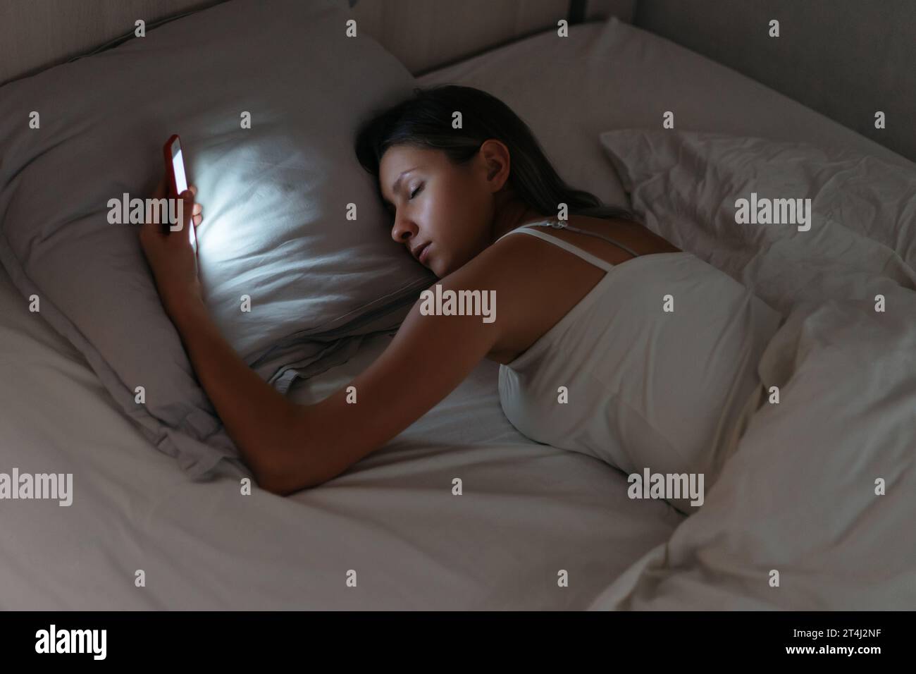Sleeping woman is holding smartphone in her hand at night. Phone ...