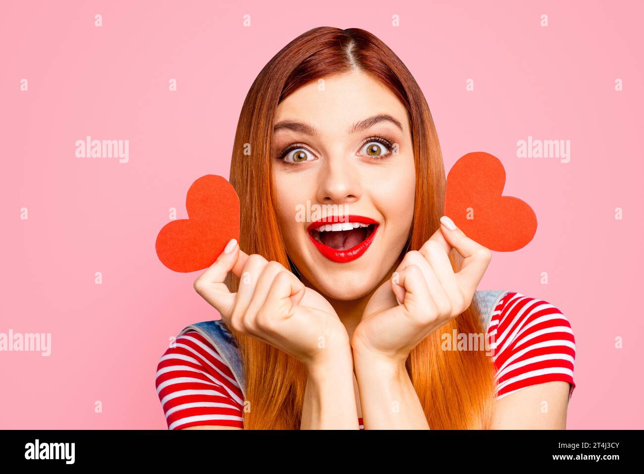 Charming and pretty young girl having two small paper heart in hands ...