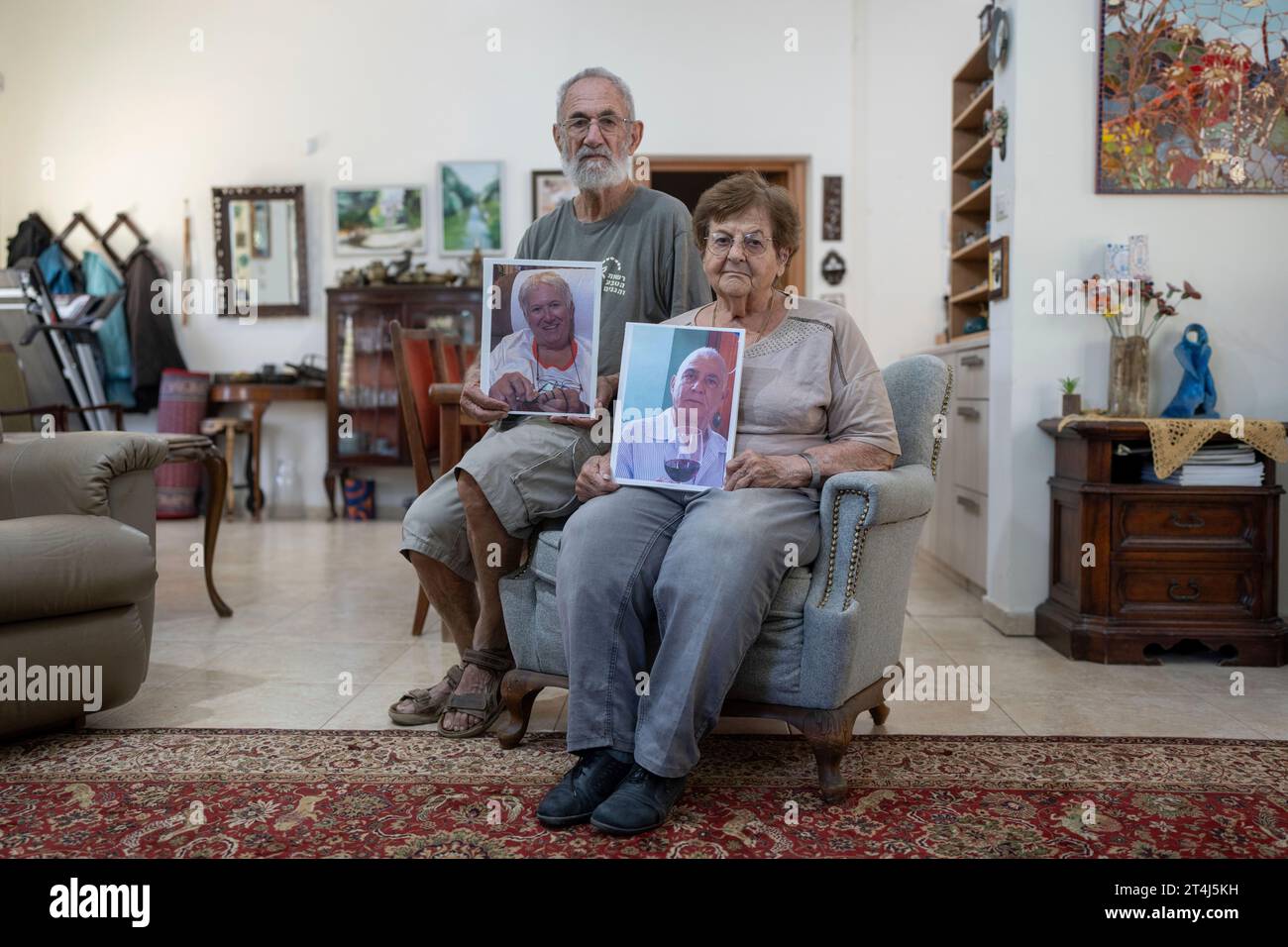 Chanan Choen, along with his wife, Edna Choen, hold up portraits of his ...