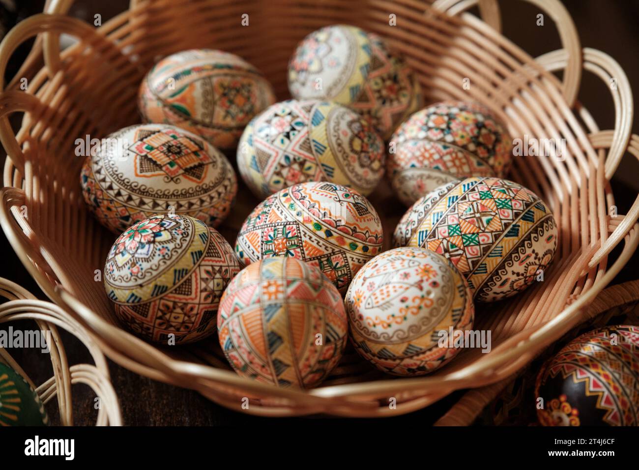 Colorful hand painted Easter Eggs in a wicker bowl. Egg decorating in ...