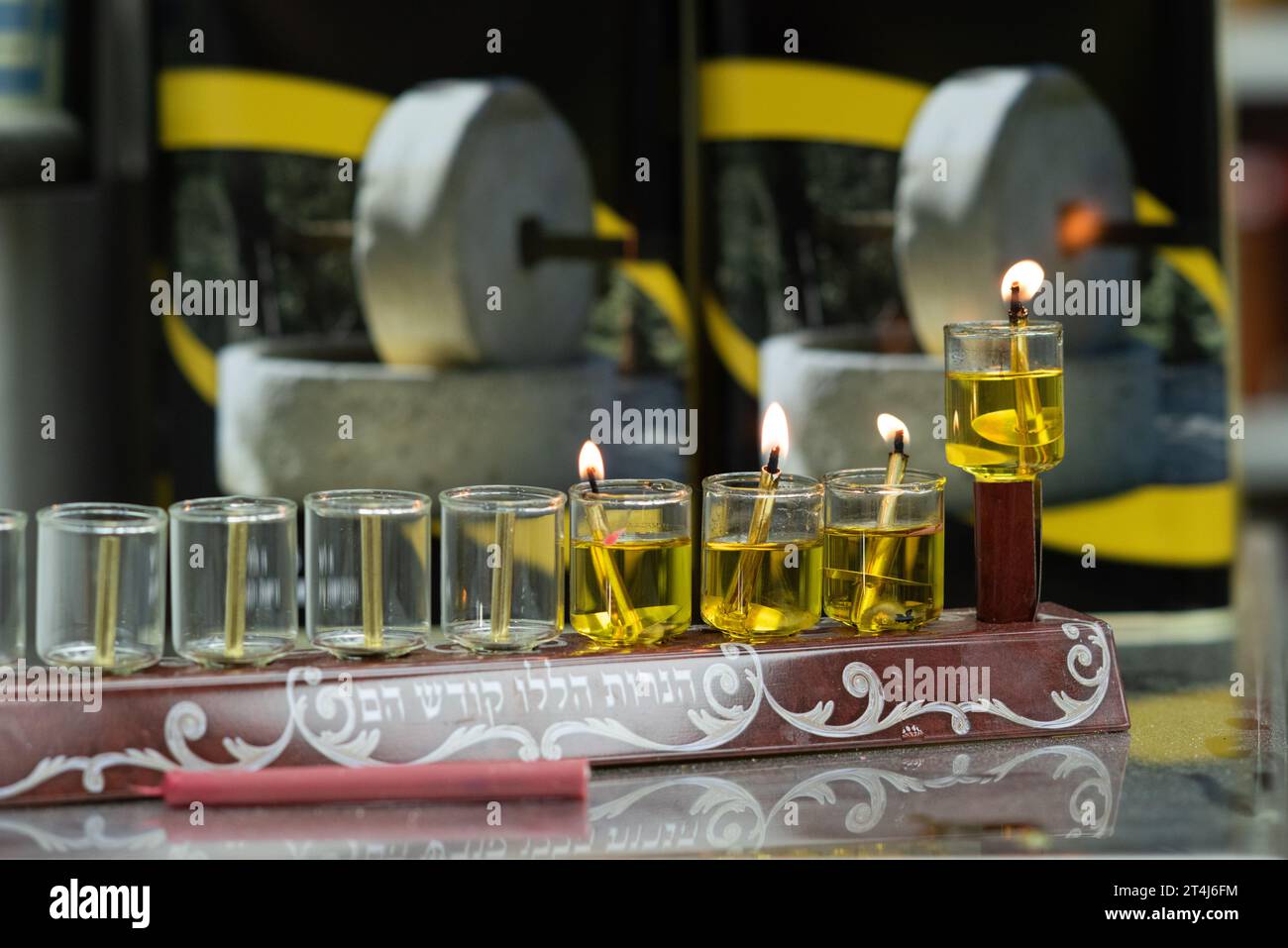 A glowing Hanukkah menorah lit with small vials of oil burns in a store ...