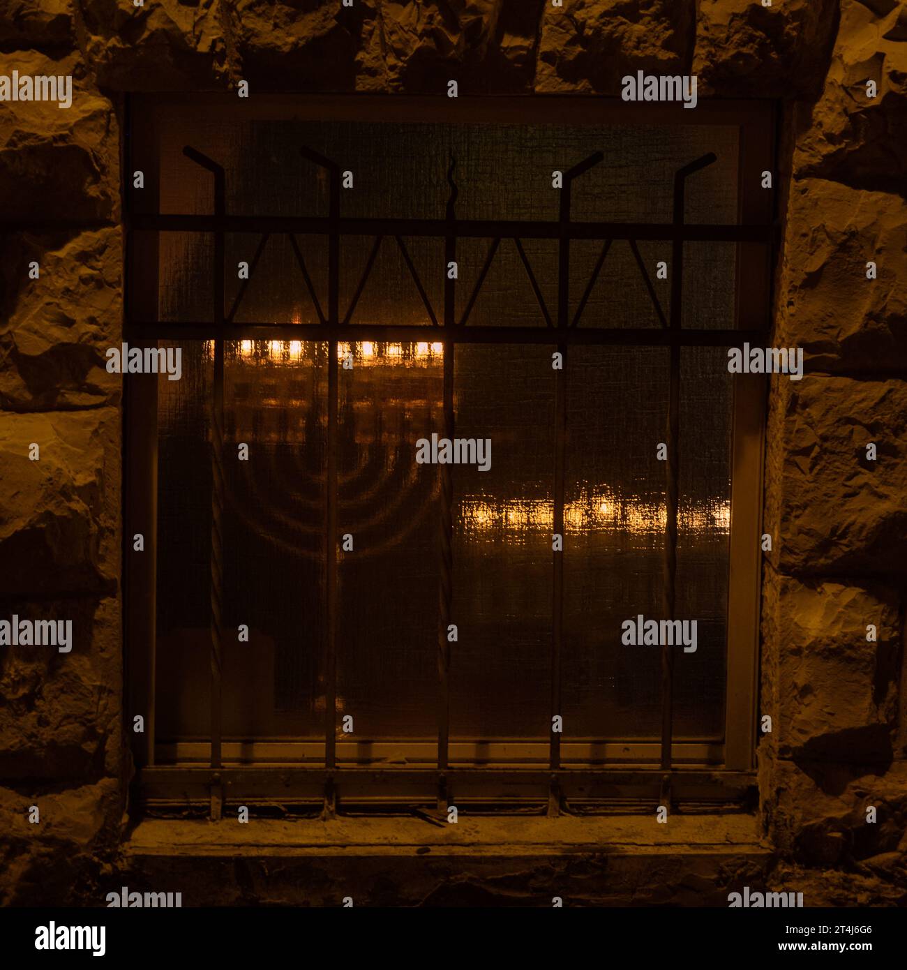 Golden glow of a Hanukkah menorah with oil lights burning in a window ...