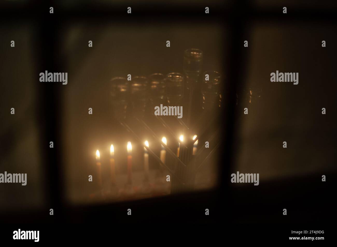 Golden glow of a Hanukkah menorah with oil lights burning in a window ...