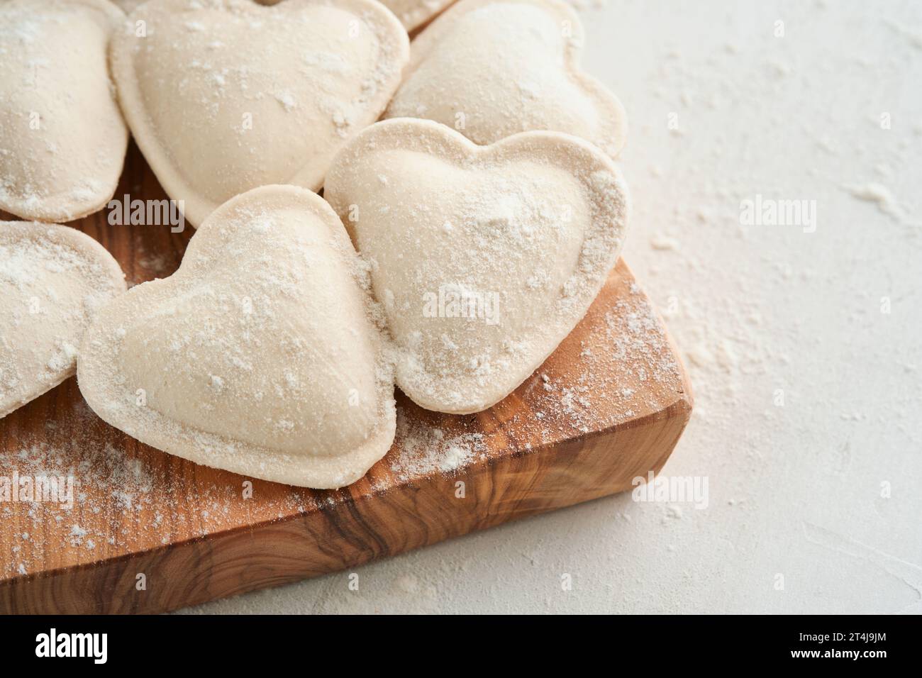 Italian ravioli pasta in heart shape. Tasty raw ravioli with flour and ...