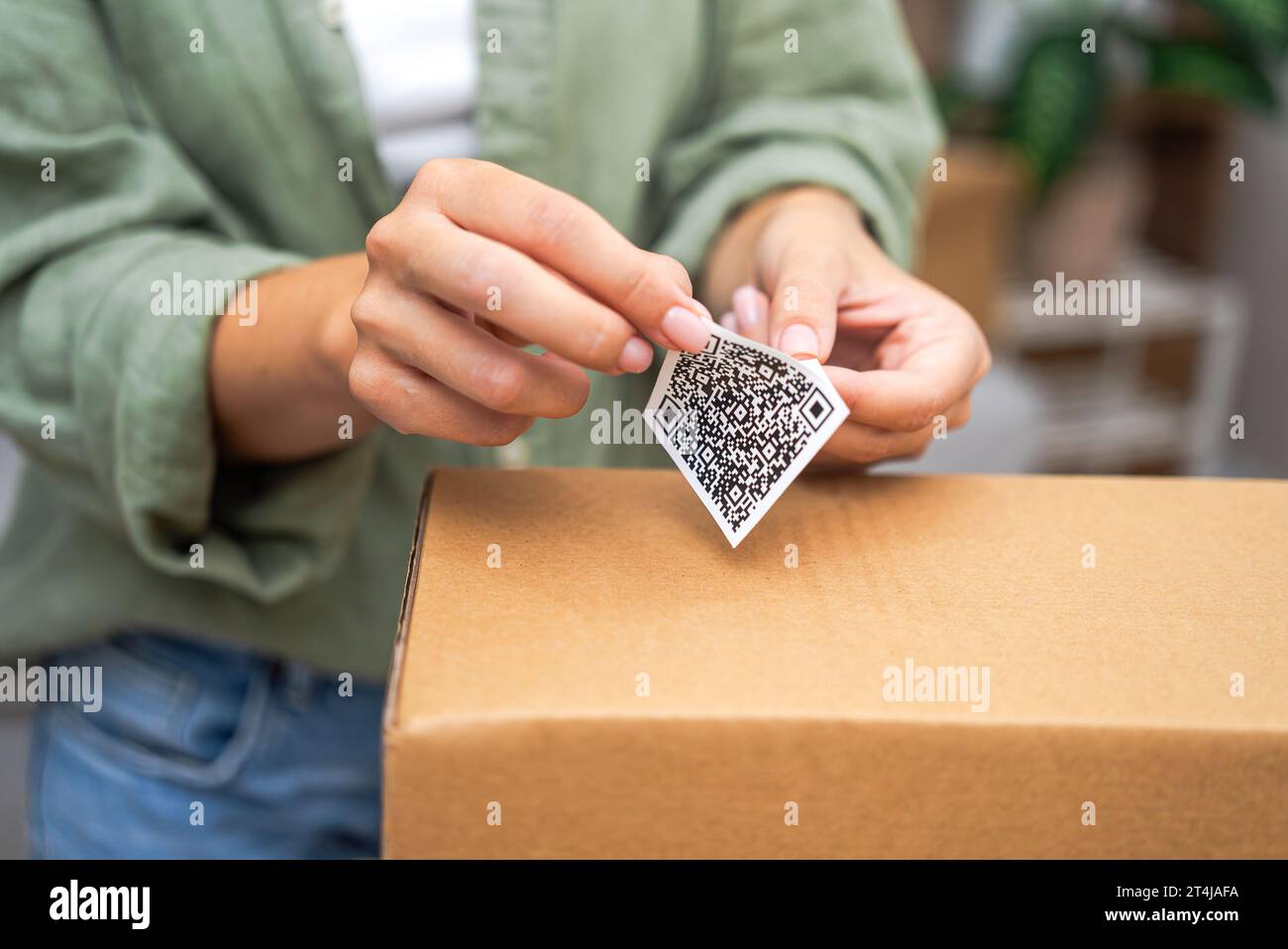 Female hands remove sticky part from sticker with barcode to send box ...