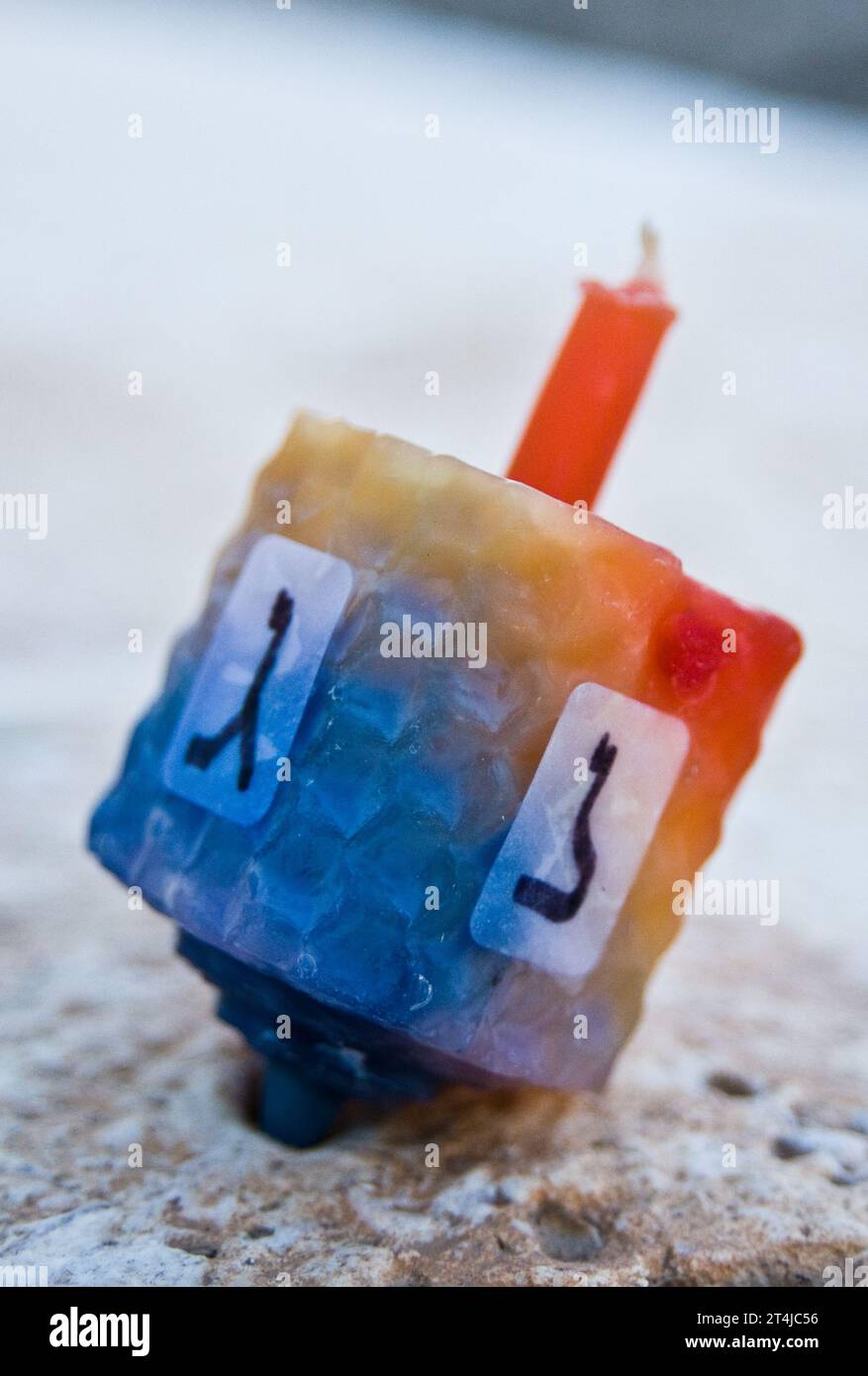A colorful, beeswax dreidel candle with the Hebrew letters "nun" and ...