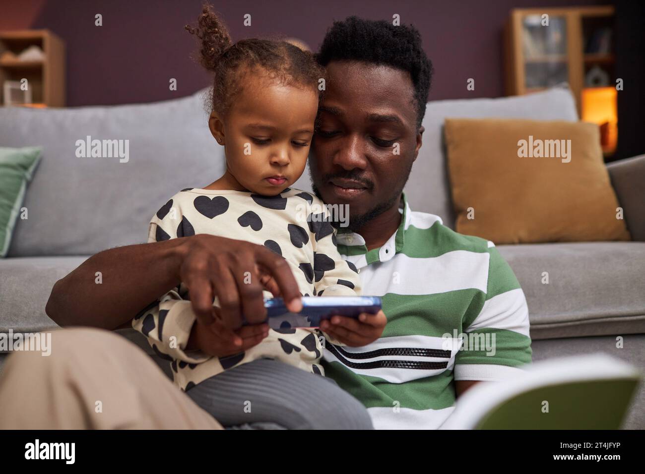 Portrait of Black father and daughter using smartphone together and ...