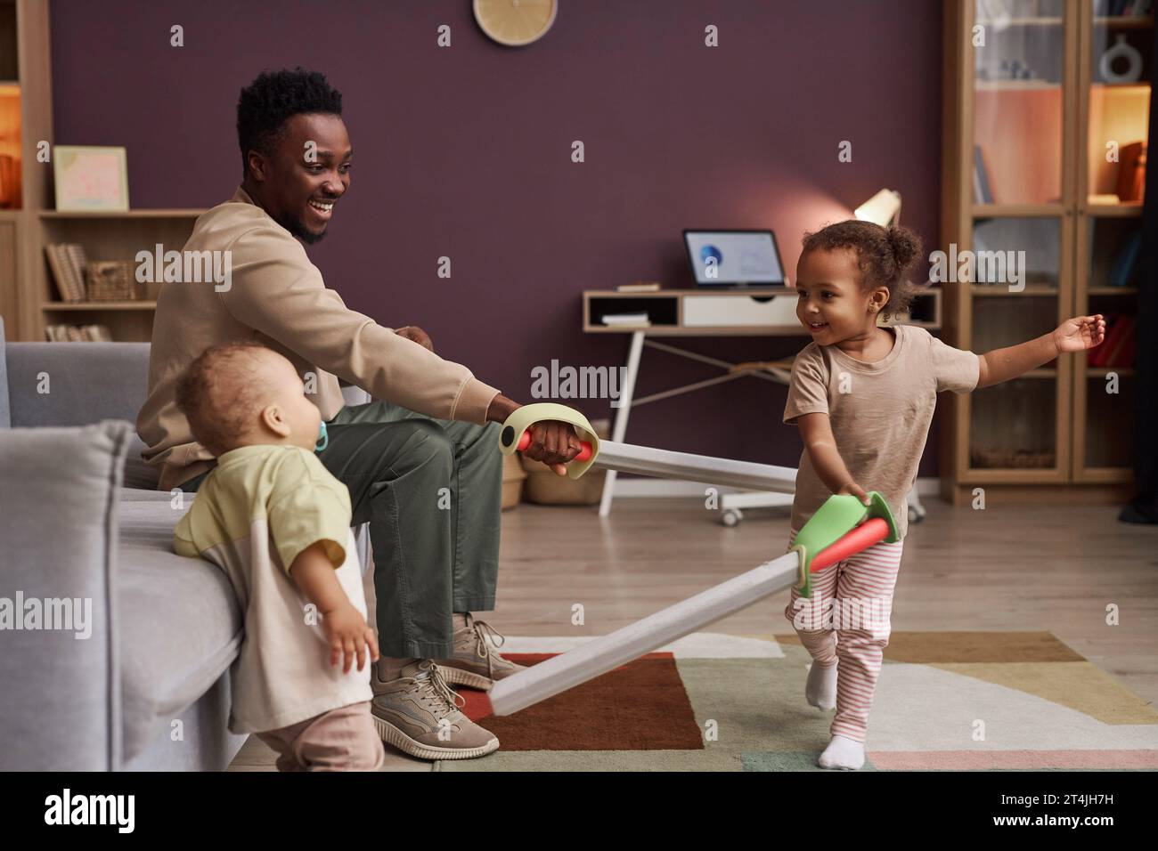 Side view portrait of young Black father playing pirates with two ...