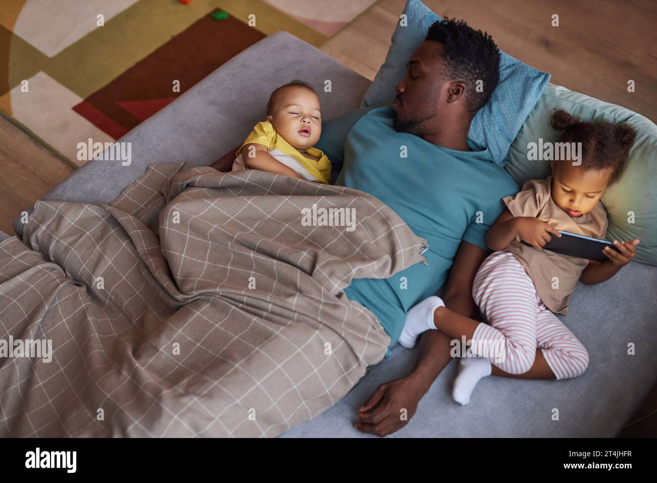 Top down view of exhausted Black father sleeping with two little kids ...