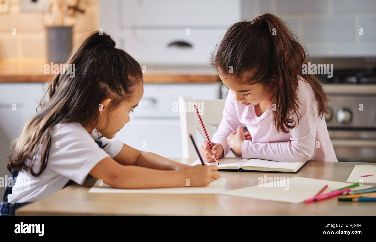 Being mischievous together. two girls completing their homework ...