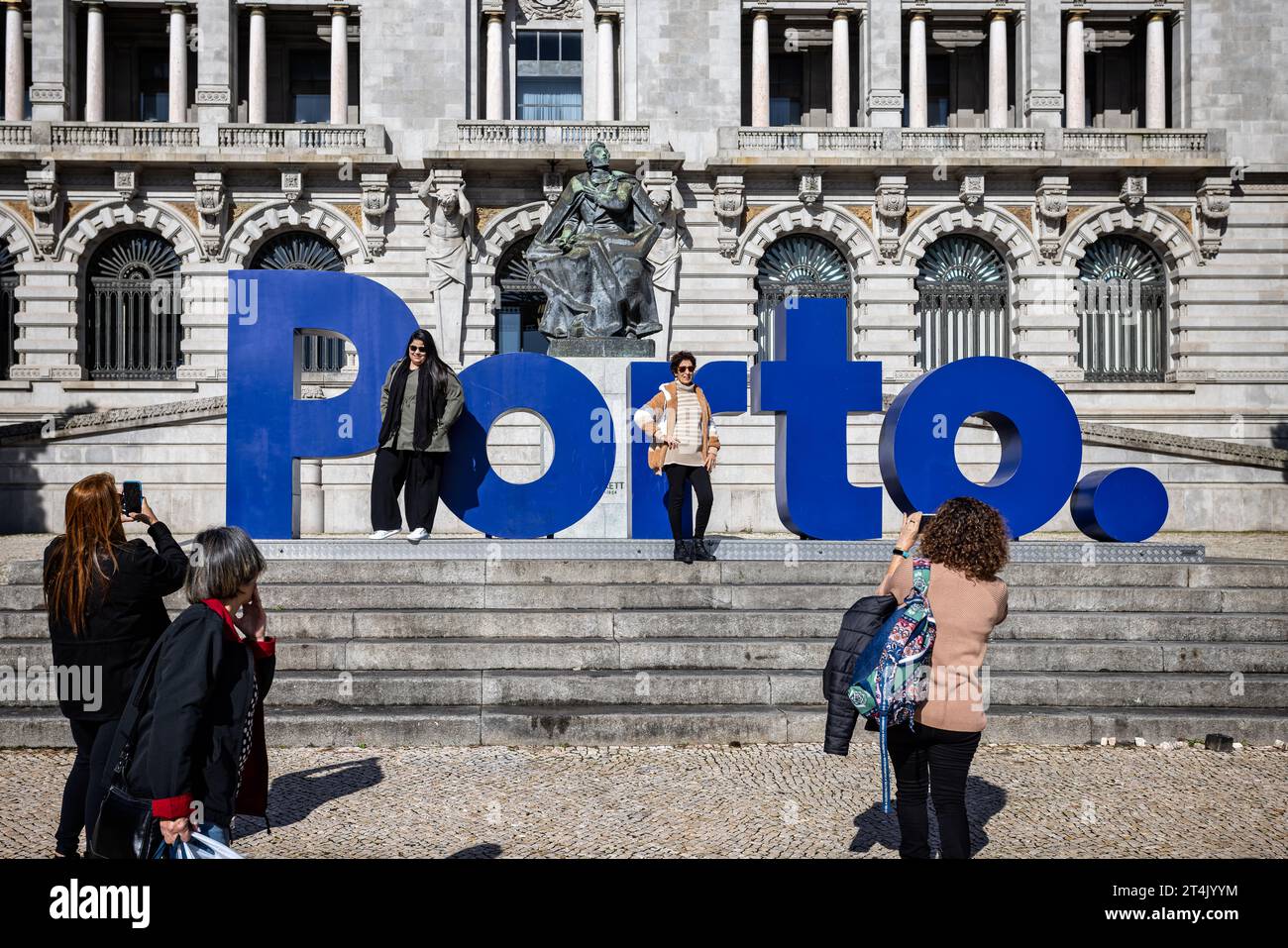 Tourists taking photographs in front of large blue Porto sign in front ...