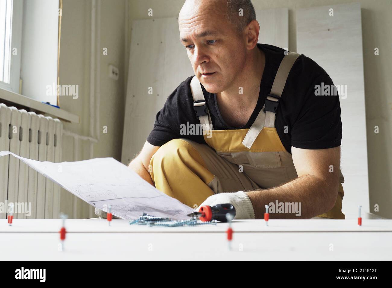 A male worker studies instructions before assembling furniture. Overall ...