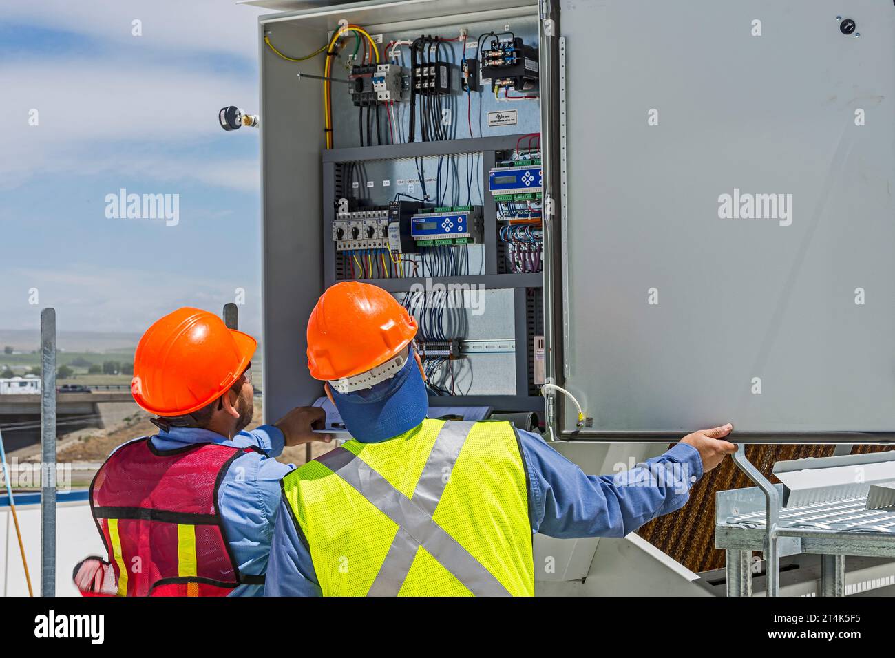 Two construction workers check the control panel of an adiabatic ...