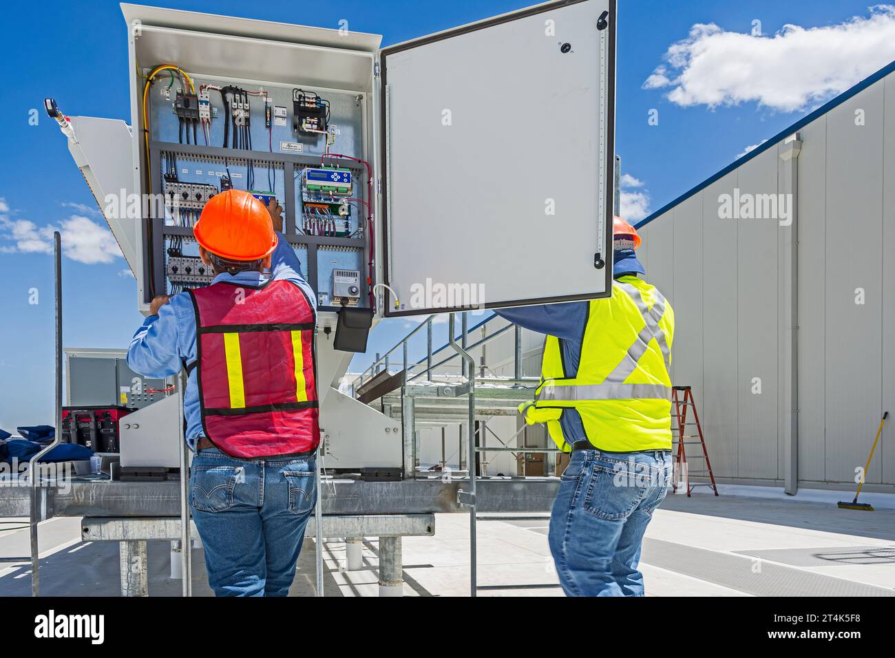 Two construction workers check the control panel of an adiabatic ...