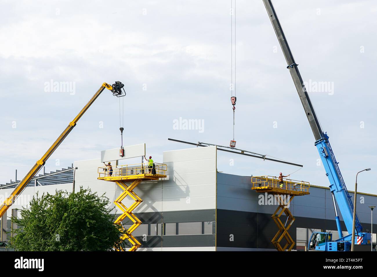 Assembly of sandwich panel walls and roof using two telescopic jib ...