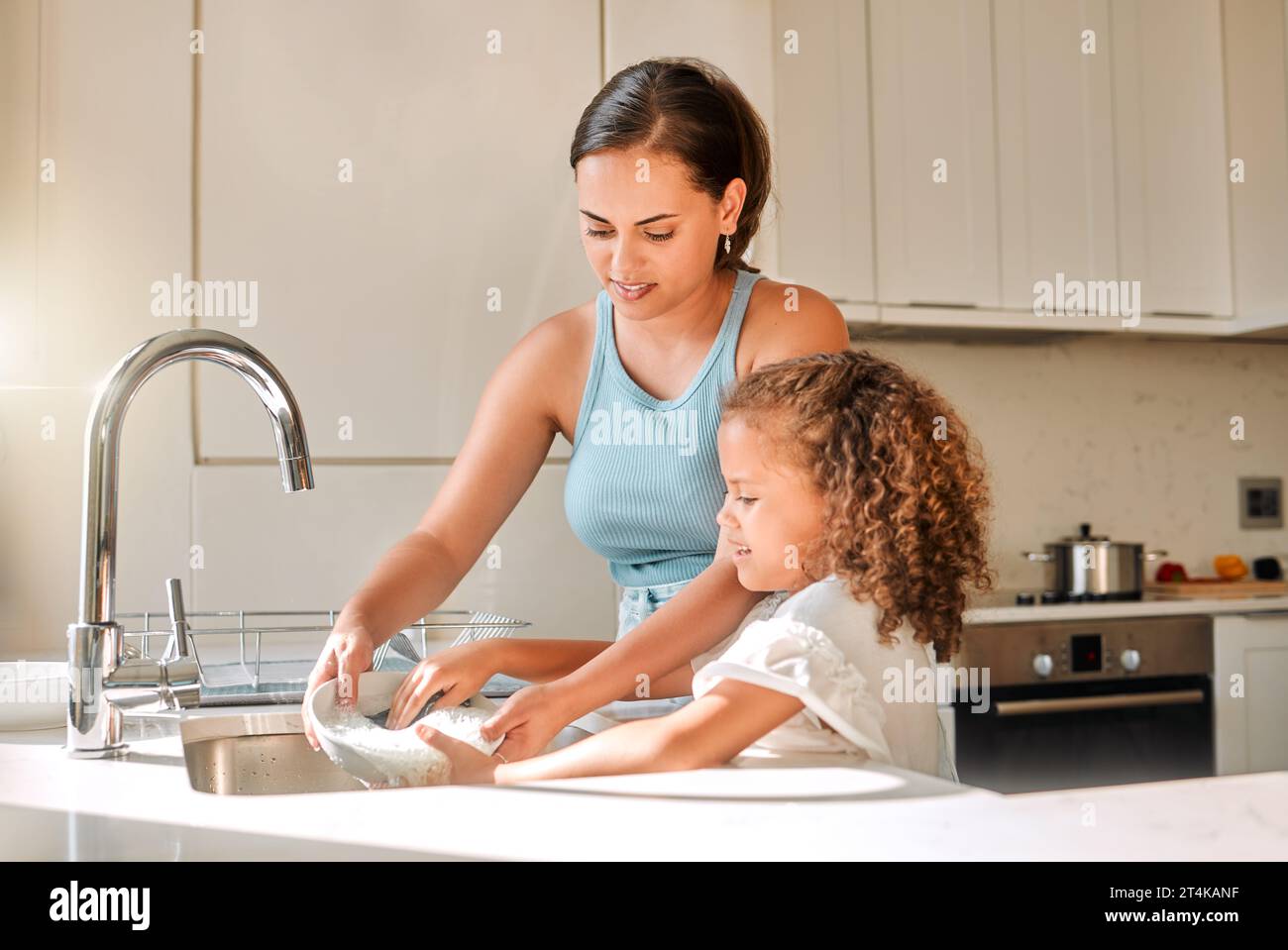 Little girl helping her mother with household chores at home. Happy mom ...