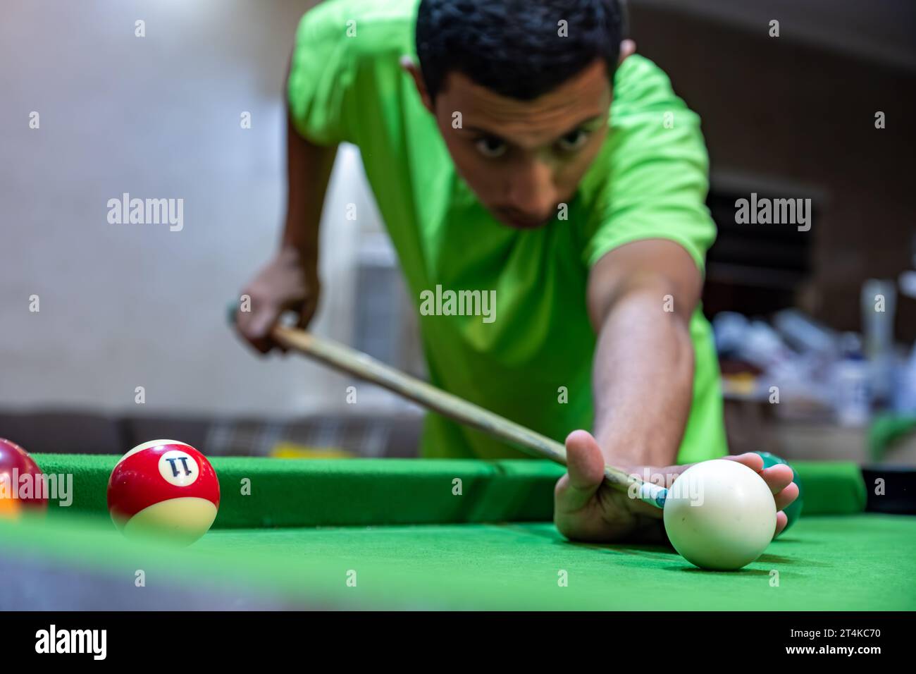 Young adult bearder male playing billiards with his friends focusing on ...