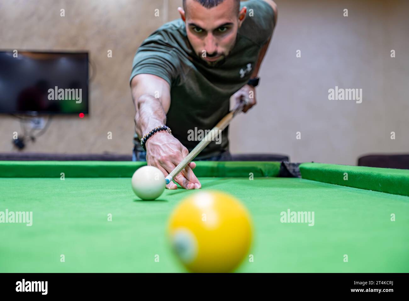 Young adult bearder male playing billiards with his friends focusing on ...