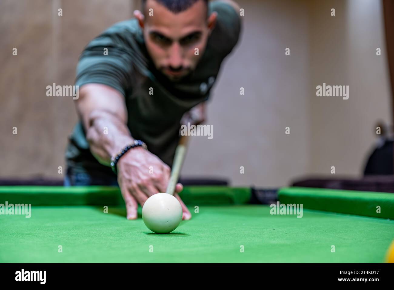 Young adult bearder male playing billiards with his friends focusing on ...